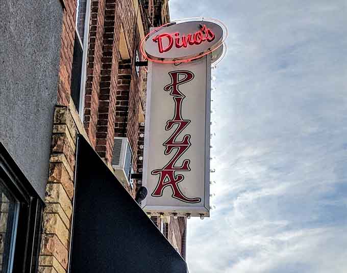 That vintage vertical sign announces "PIZZA" to the world, a proud declaration that carbs and cheese await within these walls.