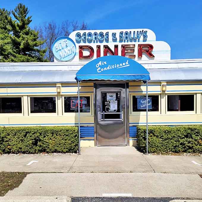 The blue awning and silver door mark the threshold between the rushed modern world and the timeless pleasure of a proper American diner experience.