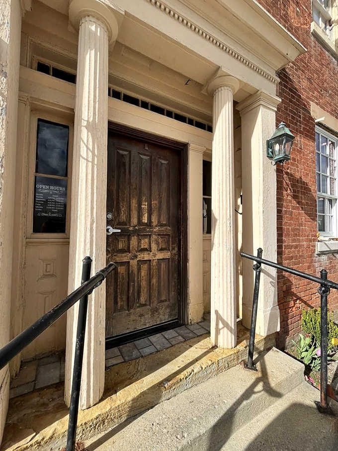 The weathered wooden door stands between two stately columns, inviting you to step back in time while your stomach steps forward toward culinary bliss.