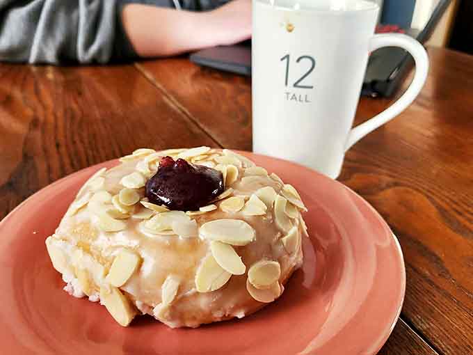 This almond-topped beauty with its jammy center sits pretty on a pink plate &ndash; the donut equivalent of getting dressed up for a special occasion.