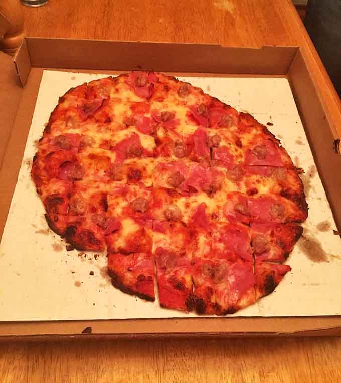A meat-lover's dream where pork products unite in perfect harmony – like a delicious family reunion on dough.