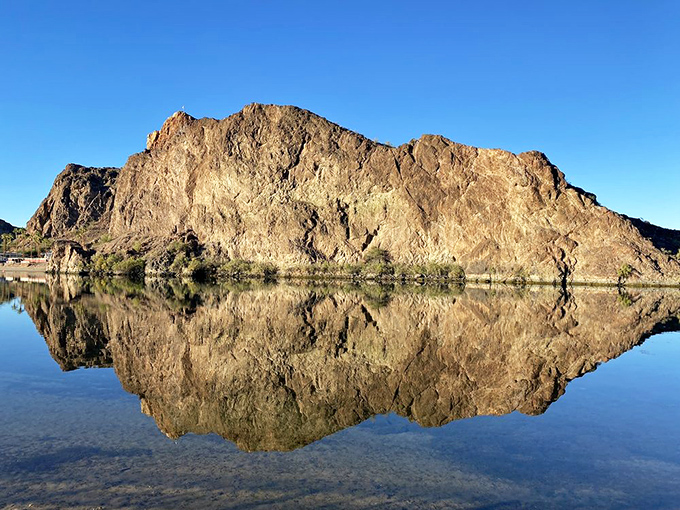Mountains reflect perfectly in the still morning water, creating a mirror image so precise it confuses fish and delights photographers.