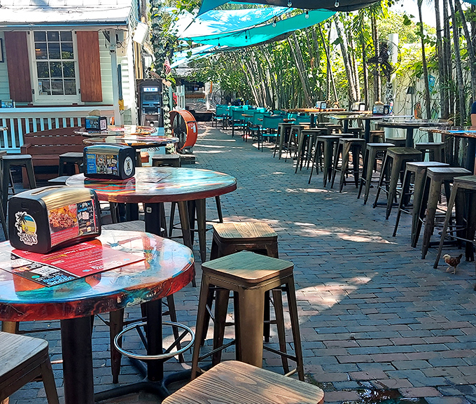 Outside seats: The perfect outdoor dining room – turquoise chairs under bamboo shade where island breezes enhance every bite in this brick-paved paradise.