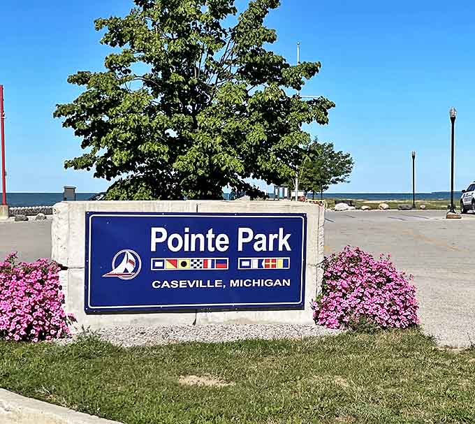 Pointe Park's welcoming sign stands sentinel, with nautical flags hinting at the maritime heritage that shaped this lakeside community.