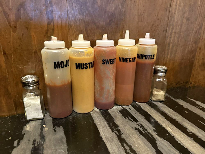 The flavor squad lines up for duty—each bottle containing liquid personality ready to customize your meat experience with tangy, sweet, or spicy notes.