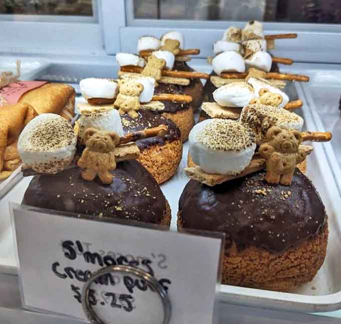 S'mores cream puffs transform campfire nostalgia into sophisticated pastry, complete with tiny teddy grahams standing guard over toasted marshmallow peaks.