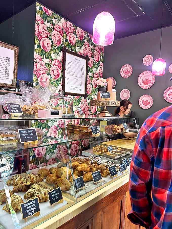 Pink floral wallpaper meets glass display case in a marriage of aesthetics and appetite&mdash;every pastry tag a promise of delight to come.