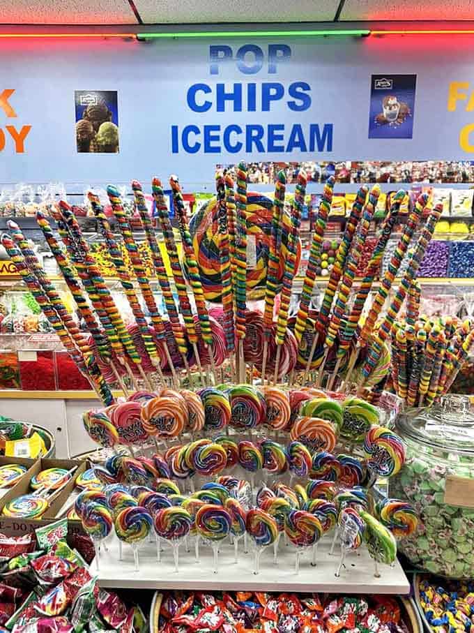 Lollipop forest! Rainbow swirls stand at attention, their hypnotic patterns promising flavor adventures that last exactly as long as your willpower to not bite.