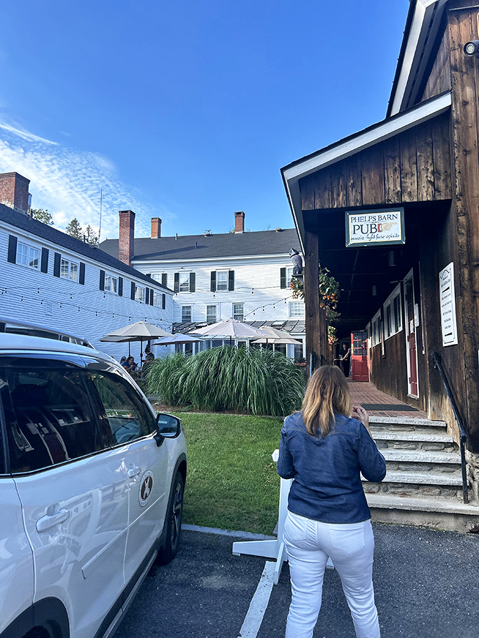 The path to Phelps Barn leads past The Old Tavern's white clapboard elegance, building anticipation for the rustic culinary adventure that awaits inside.