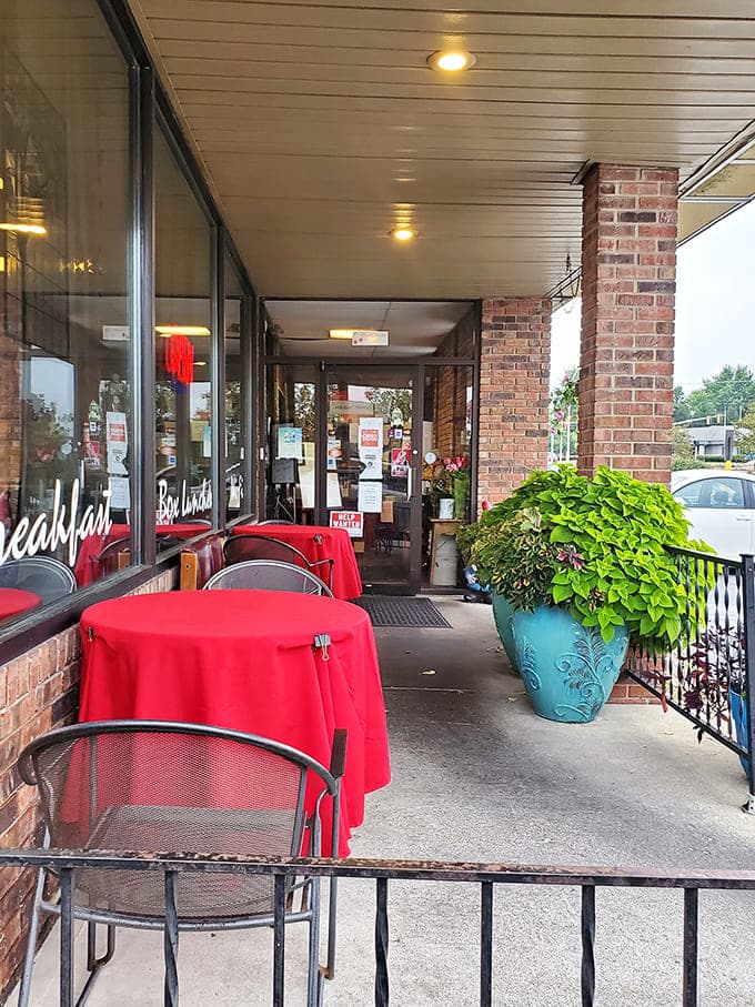 The outdoor seating area offers a charming spot for fair-weather dining, with bright red tablecloths adding a pop of cheer to the brick exterior.