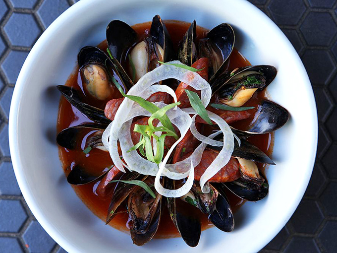 Mussels arranged like black petals in a spicy tomato broth, their oceanic sweetness playing counterpoint to the sauce's vibrant acidity.