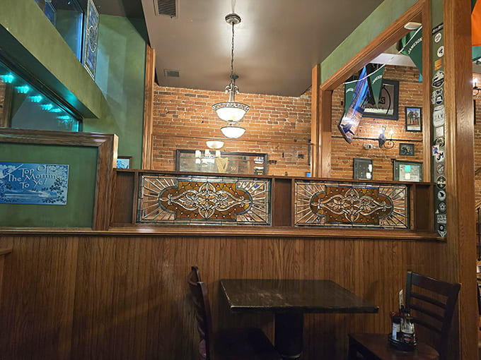 Cozy booths with stained glass accents offer intimate spaces for quiet conversations, while exposed brick walls add warmth to the authentic pub atmosphere.