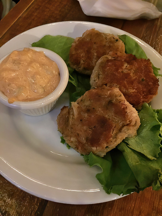 These golden-brown crab cakes arrive perfectly crisp on the outside, tender within, and served with a zesty sauce for dipping.