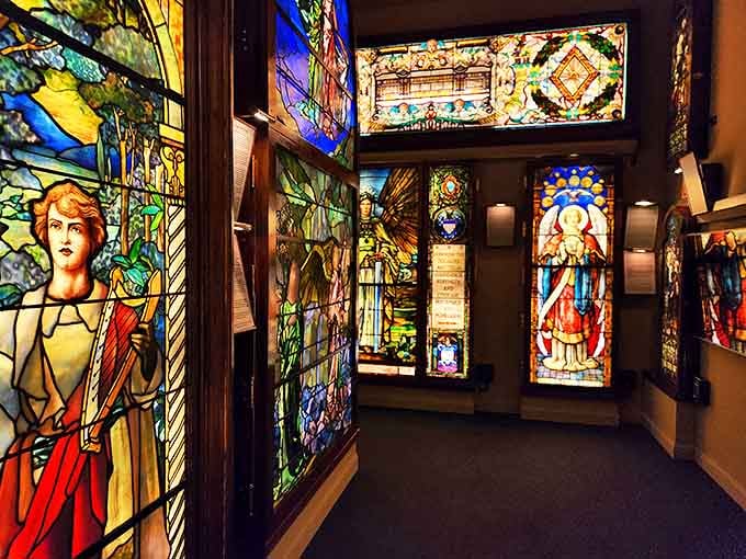 Stained glass masterpieces line this corridor like illuminated pages from a medieval manuscript, each panel a radiant chapter in the story of light and color.