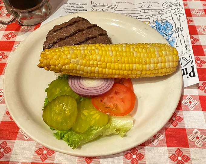 A perfectly grilled burger alongside sweet corn and fresh vegetables &ndash; proof that even the "lighter" options here deliver heavyweight flavor.