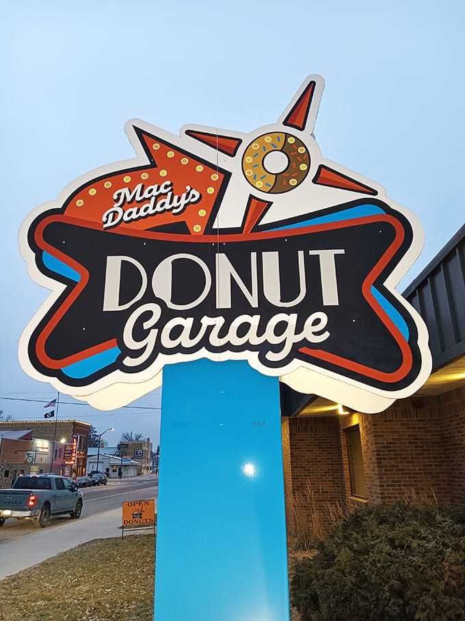 The iconic MacDaddy's Donut Garage sign glows against the Minnesota sky, a retro-inspired beacon guiding sugar-seekers to their sweet destination.