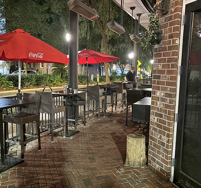 Red umbrellas stand guard over brick-paved serenity, offering al fresco dining under Florida's generous evening sky.