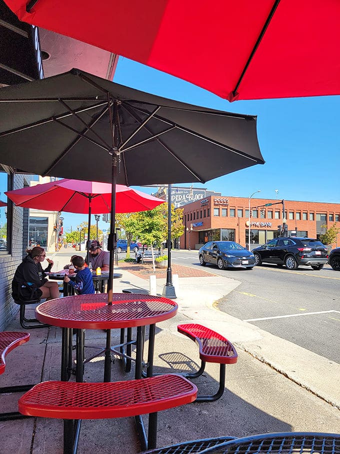 Red umbrellas shade outdoor tables where diners enjoy their meals while watching the world go by &ndash; the perfect spot for people-watching with a side of fries.