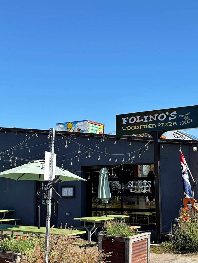 The outdoor dining area transforms simple green tables into community gathering spots where pizza lovers bask in Vermont sunshine and wood-fired goodness.