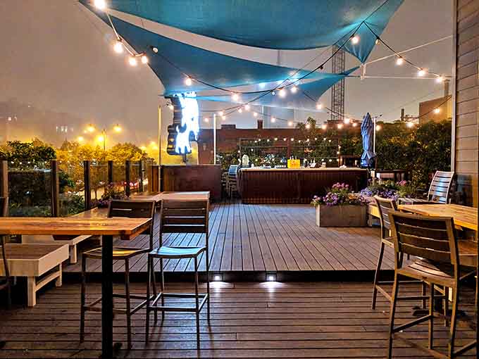 As evening falls, string lights transform the deck into a magical dining space where city views complement the innovative menu offerings.