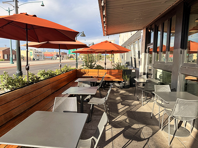 Mesa sunshine bathes the inviting patio where orange umbrellas and wooden planters create an urban oasis for sandwich enthusiasts.