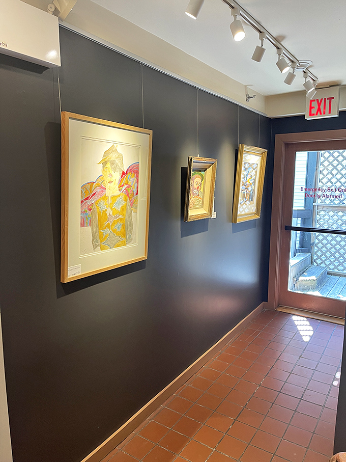 The gallery's stark black walls create the perfect backdrop for vibrant artwork, allowing each piece to command attention in this carefully curated space.