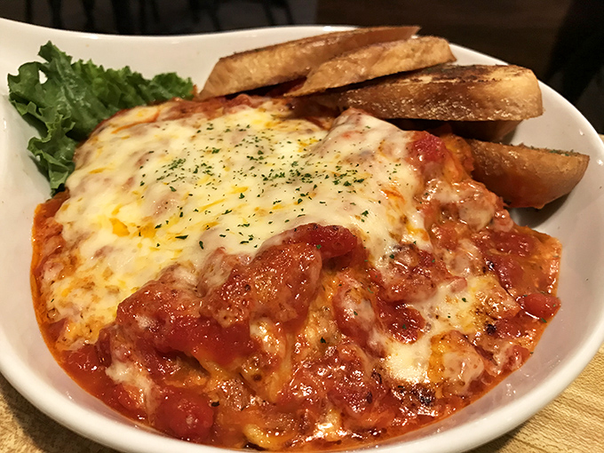 Baked pasta bubbling with cheese and rich tomato sauce, accompanied by garlic toast perfect for the sacred ritual of sauce-sopping.