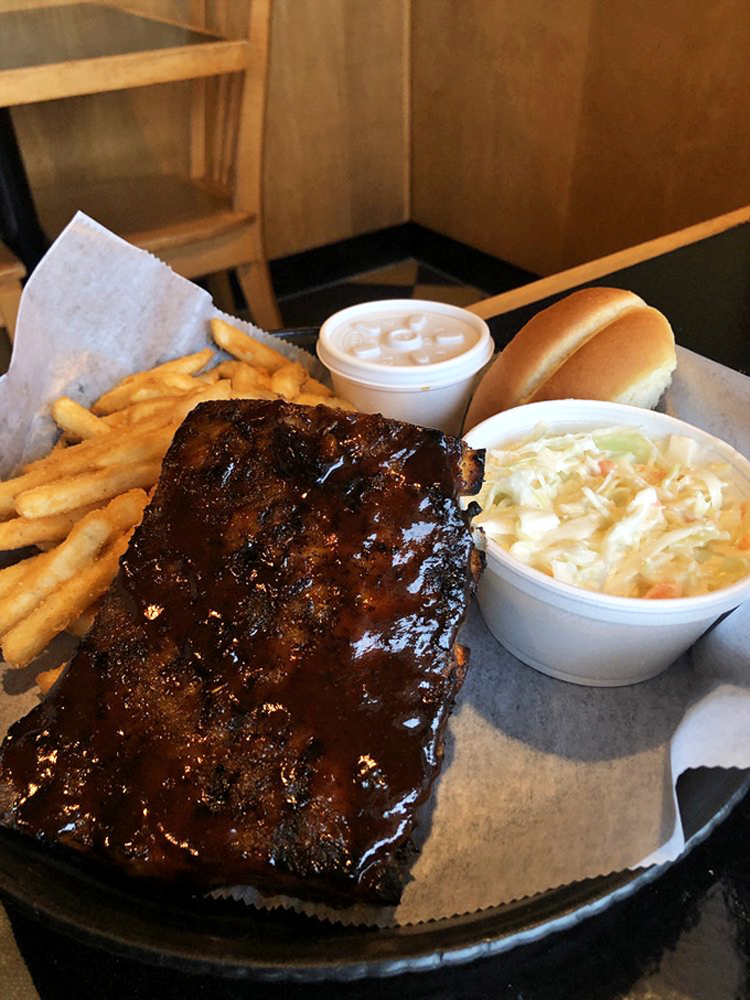 A hearty plate of saucy ribs served with fries and classic sides, perfect for serious barbecue cravings.