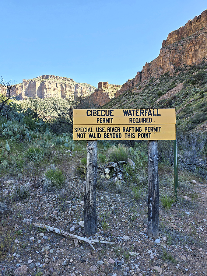 Your first clue that something special awaits: the permit sign marking the boundary between ordinary hiking and extraordinary adventure at Cibecue Falls.