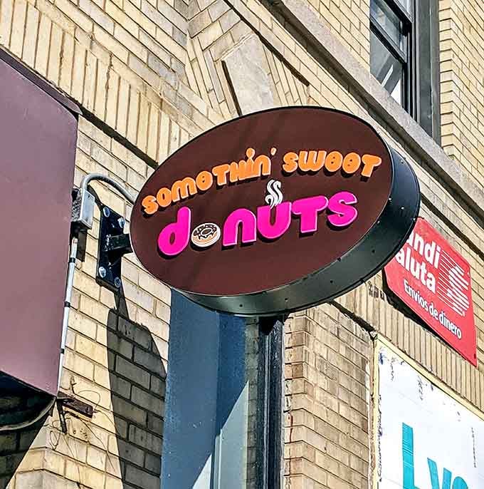 The "Somethin' Sweet Donuts" sign serves as a beacon for sugar-seekers, its playful typography hinting at the whimsical treats that await inside.