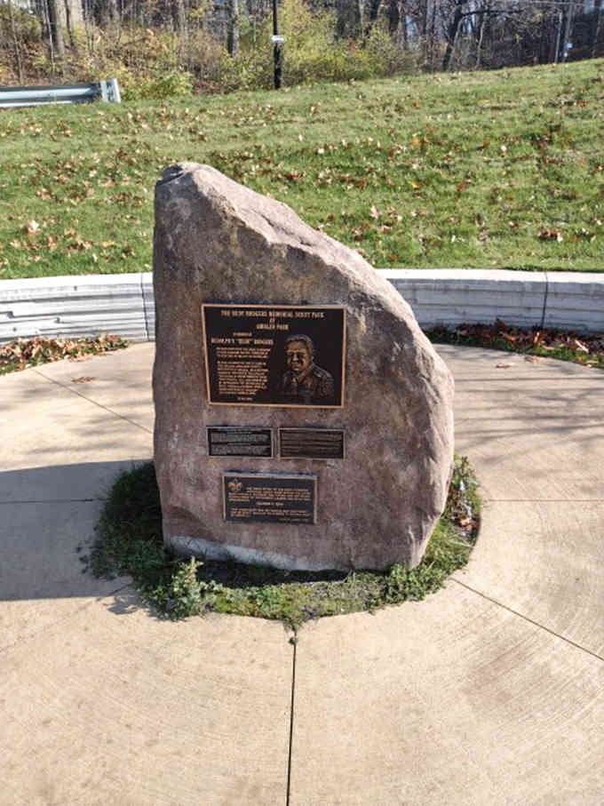 A silent stone sentinel guards memories of the past, its bronze plaque whispering stories to those who pause to listen.