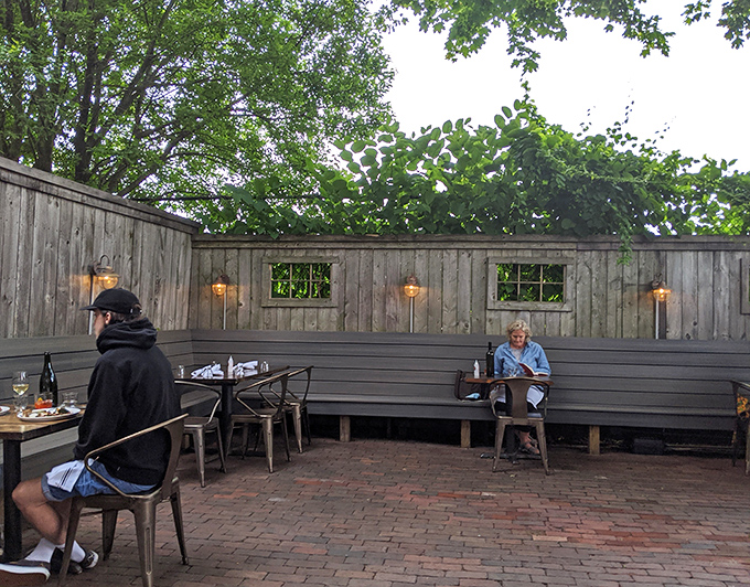 The secluded back patio offers a tranquil dining retreat, where wooden benches and ambient lighting create the perfect atmosphere for lingering conversations.