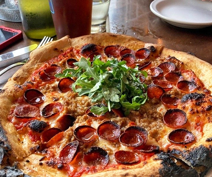 Wood-fired pizza perfection &ndash; blistered crust, melty cheese, and pepperoni that curls into little cups of savory goodness. Even the salad garnish looks excited!