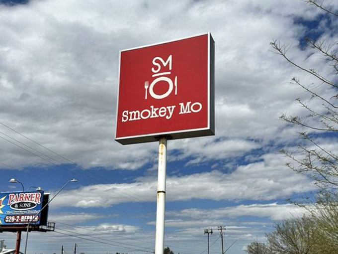 The Smokey Mo sign stands tall against Arizona's dramatic sky, a landmark for those seeking authentic barbecue in Tucson.