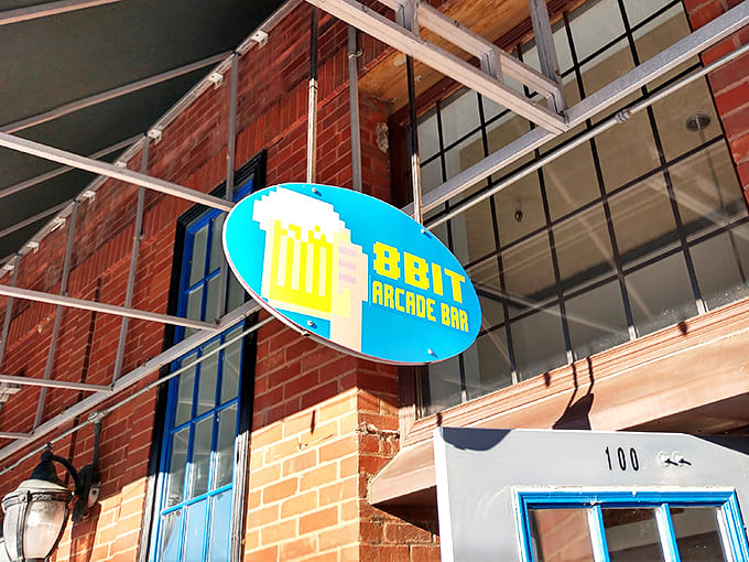 The 8bit Arcade Bar sign hangs like a beacon for grown-ups who still remember when entertainment required quarters and skill.