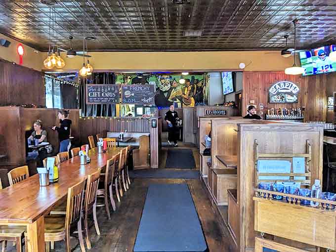 Tin ceilings, wooden booths, and colorful murals create the perfect neighborhood pub atmosphere where everyone feels welcome.