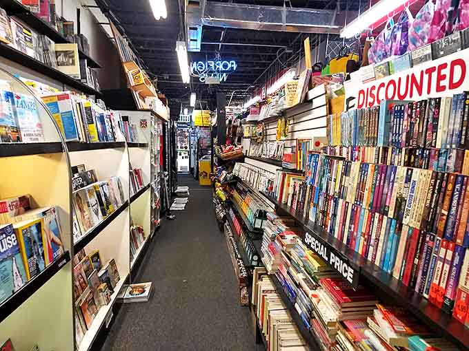 Narrow aisles create a literary canyon effect, where browsers must navigate walls of knowledge that seem to lean in with curiosity about their visitors.