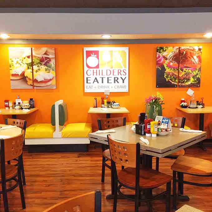 Bright orange walls and cozy seating create an inviting atmosphere where breakfast dreams come true every morning.