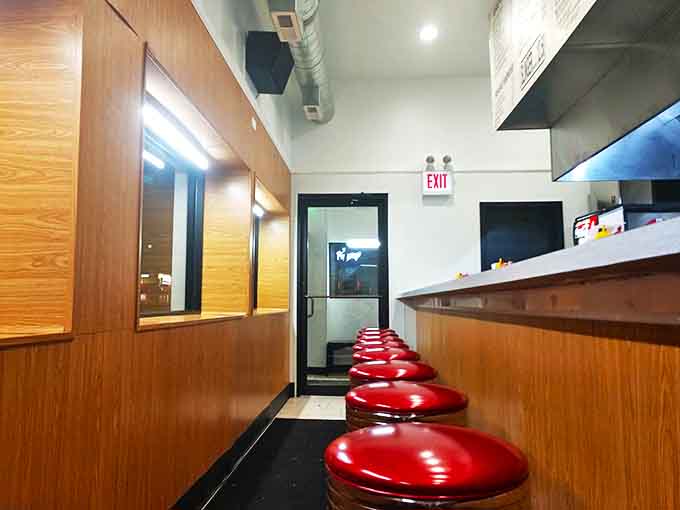 Classic red counter stools line the narrow interior, offering front-row seats to the breakfast theater happening on the grill.