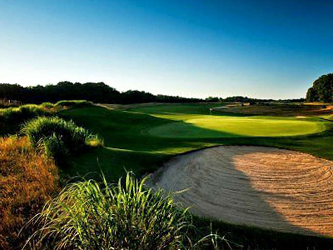 Morning light caresses the emerald fairways of South Haven's golf course, where sand traps serve as mere practice for beach adventures to follow.