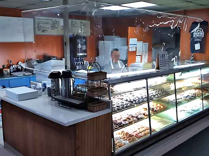 Behind the counter, donut magic happens daily. The bright display cases showcase an array of freshly made treats waiting for their moment of glory.