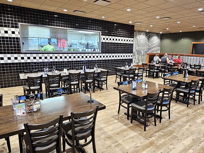 Black and white tiles create a classic pizzeria backdrop while the open kitchen invites diners to watch culinary magic unfold.