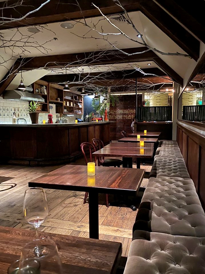 Rustic elegance defines Primo's interior, where white-painted branches create an enchanted forest ceiling above polished wood tables and tufted banquettes.