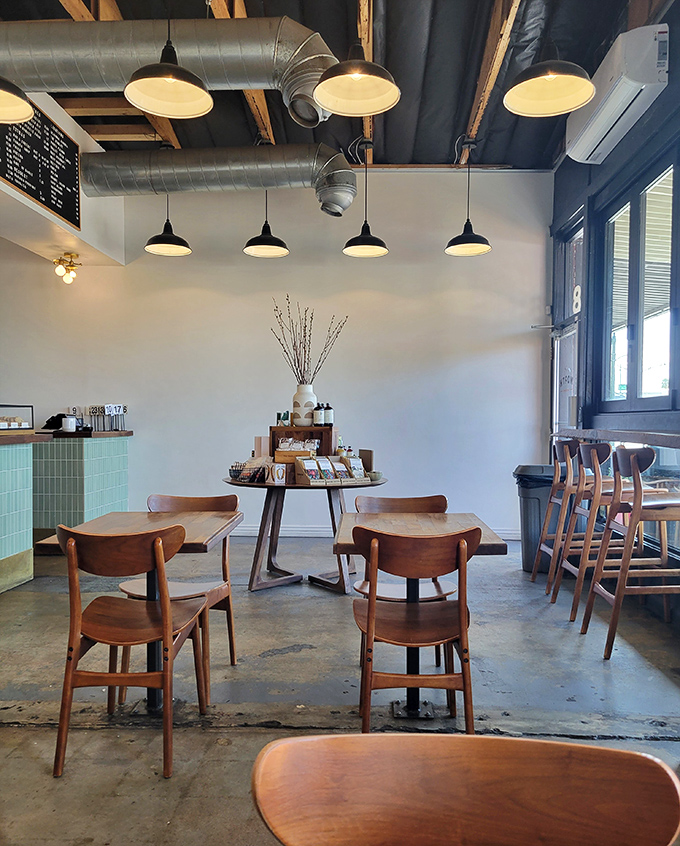 Mid-century modern meets industrial chic in this airy space where wooden chairs and exposed ductwork create an atmosphere of casual sophistication.