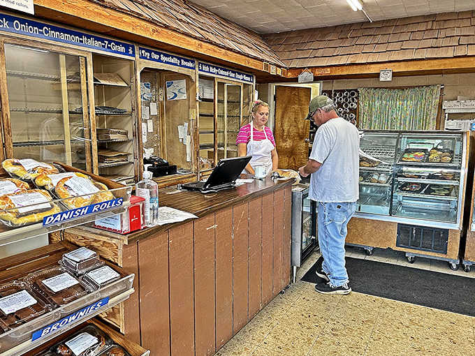 A moment of bakery magic unfolds at the counter, where friendly staff turn everyday transactions into warm, neighborhood connections.
