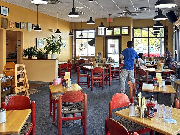 Warm yellow walls and vibrant red chairs create an atmosphere that's both energetic and cozy—like walking into a friend's kitchen where something amazing is always cooking.