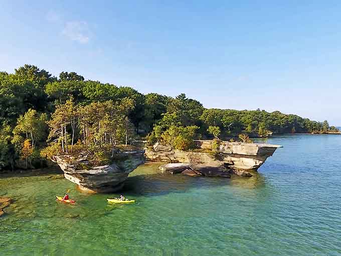 Colorful kayaks dot the turquoise waters near Michigan's thumb, where paddlers discover hidden coves and limestone formations along the shoreline route.