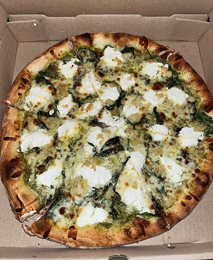 This pesto ricotta masterpiece isn't just pizza &ndash; it's edible art with dollops of creamy cheese floating on a sea of vibrant basil.