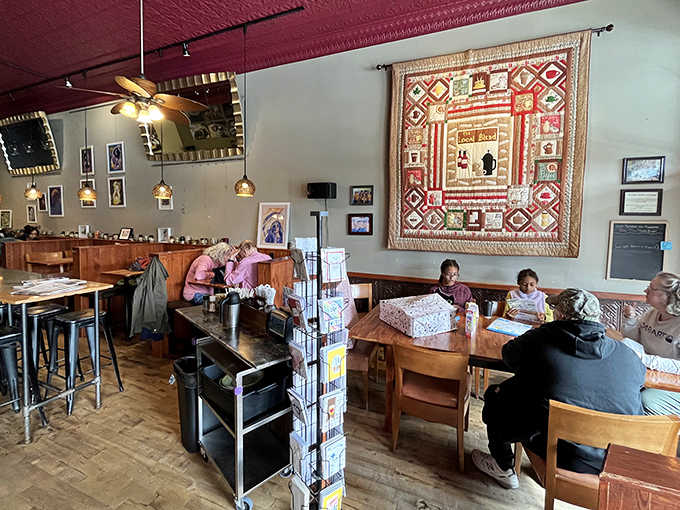 Inside, vintage charm meets modern comfort with that stunning red tin ceiling and cozy wooden booths where conversations flow as freely as the coffee.