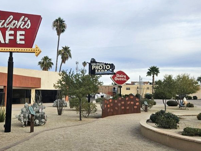 Ralph's Cafe sign stands sentinel among desert plants, its vibrant glow promising comfort food and nostalgia in equal, delicious portions.
